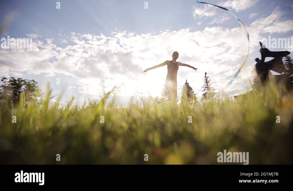 Rhythmic gymnastics. Dance young gymnast with ribbon on sunset sky ...