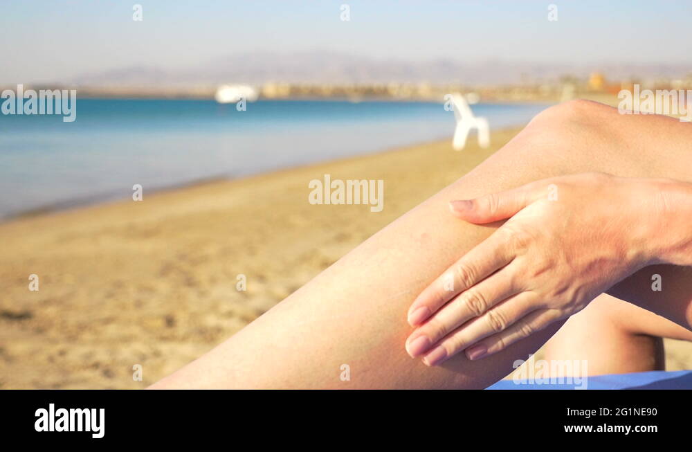 Girl with beautiful legs rubbed into the skin sunscreen on a sea ...