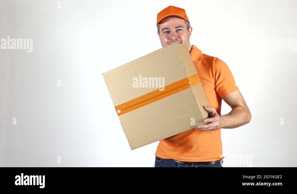 Delivery man in orange uniform throwing a big parcel at the camera ...