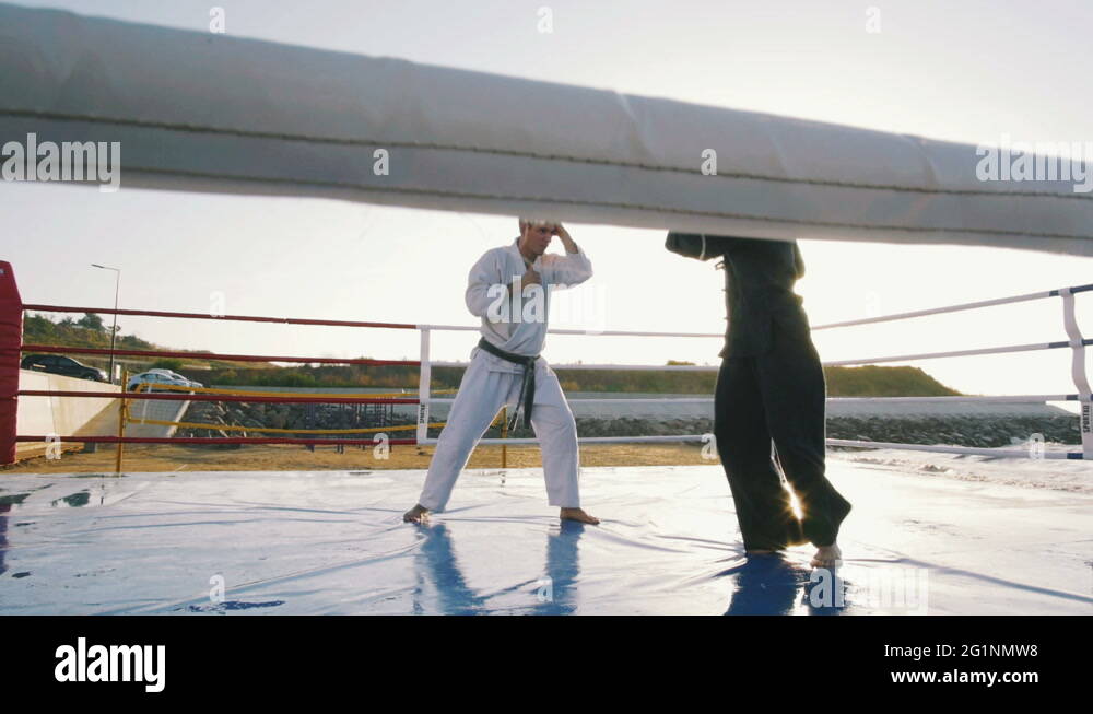 Two professional karate fighters are fighting on the beach boxing ring ...