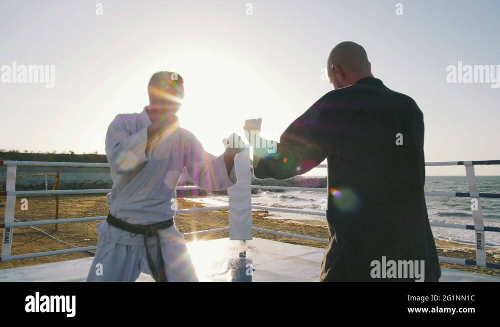 Two professional karate fighters are fighting on the beach boxing ring ...