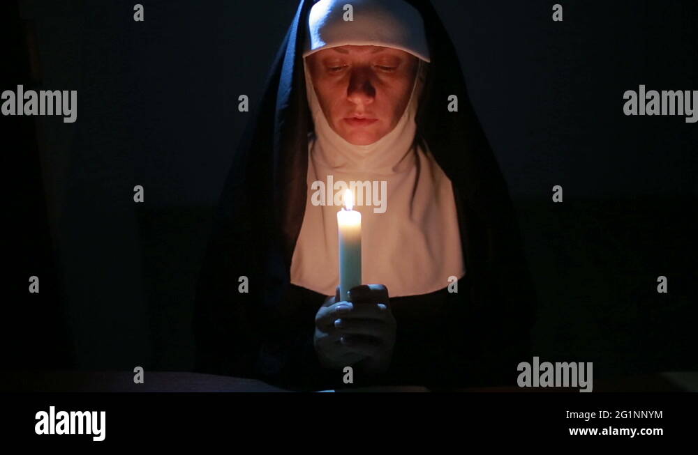 woman nun praying at night. burning candles. Woman in clothes nuns ...