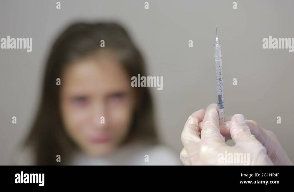 little girl is afraid of the doctor with a syringe. baby cries afraid ...