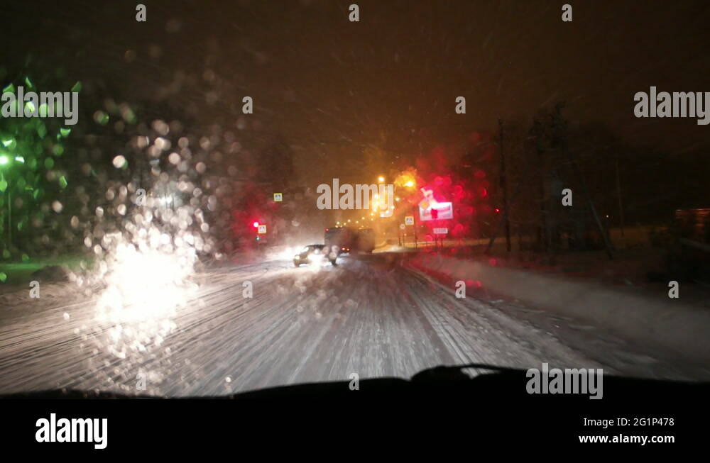 Traffic light on roadcross during night blizzard. Car inside view. POV ...