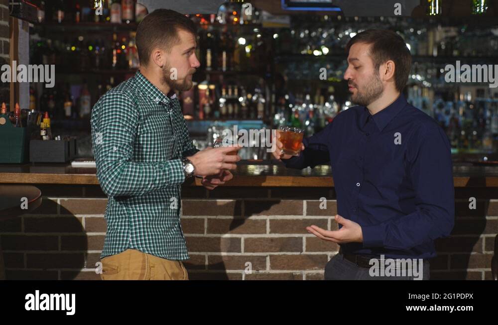 two young man talking at counter. two friends standing in bar and ...