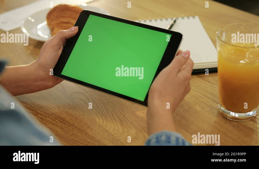 Close-up of woman's hands scrolling down page on tablet with green ...