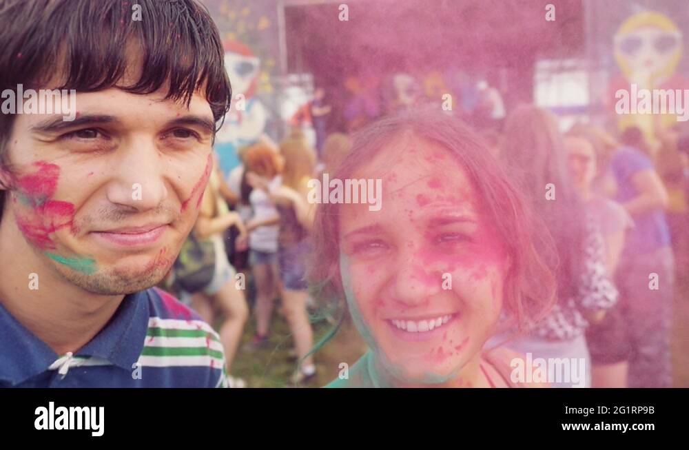 Young woman and man colorful powder laughing at Holi party dancing and ...