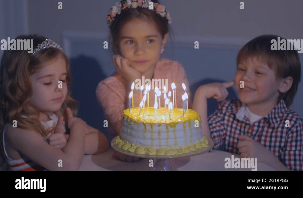 little kids sit at red table with cake. Happy group of children at ...