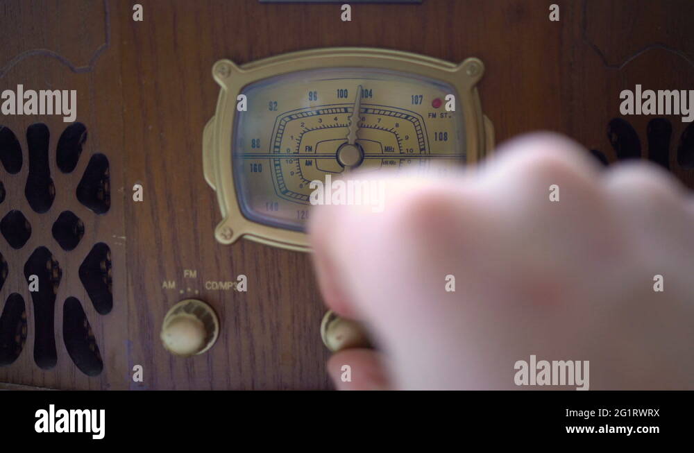 The hand of a man turns the dial on an old vintage radio. Concept: look ...