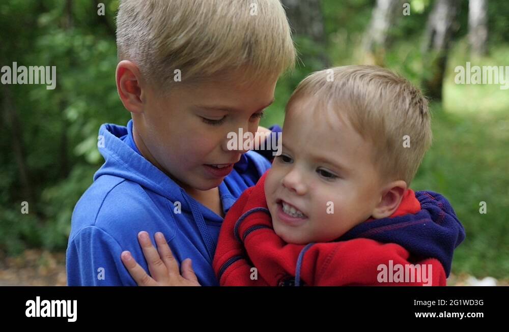 The boy hugs his younger brother and holds him on his arms Stock Video ...