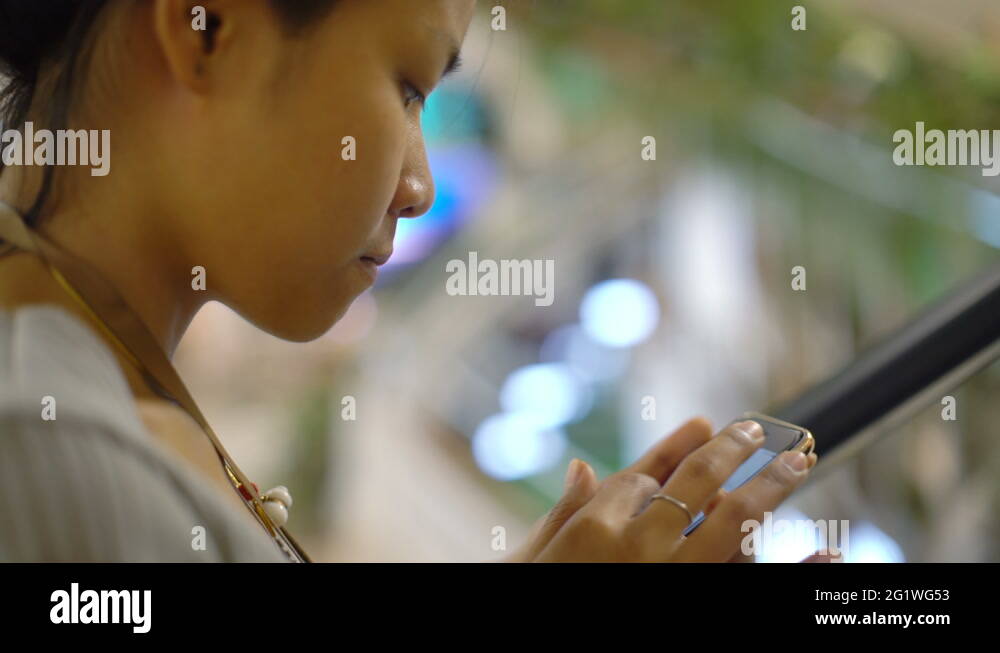 Woman swipes her phone while lifting on escalator in mall 4k UHD ...