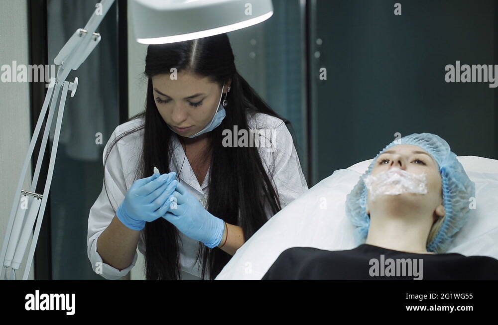 Female doctor picking up medication into a syringe and prepares it for ...