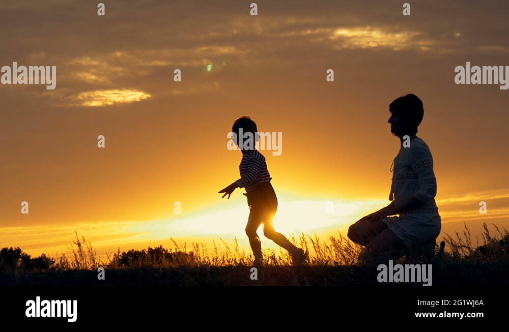 a silhouette of a happy young boy child running into the arms of his ...