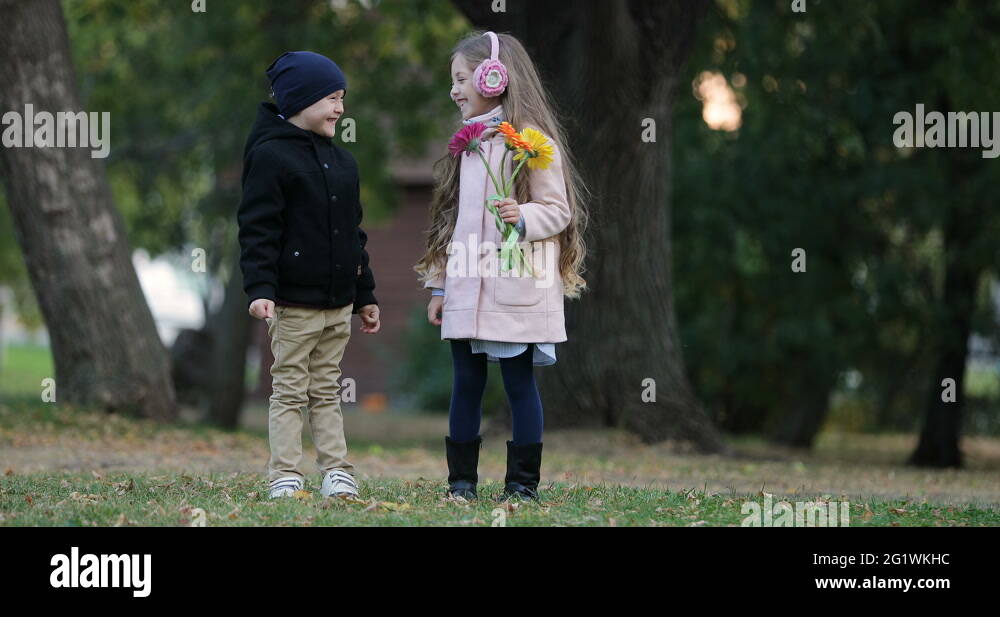 Two children stand and laugh in the park. Little boy and a little girl ...