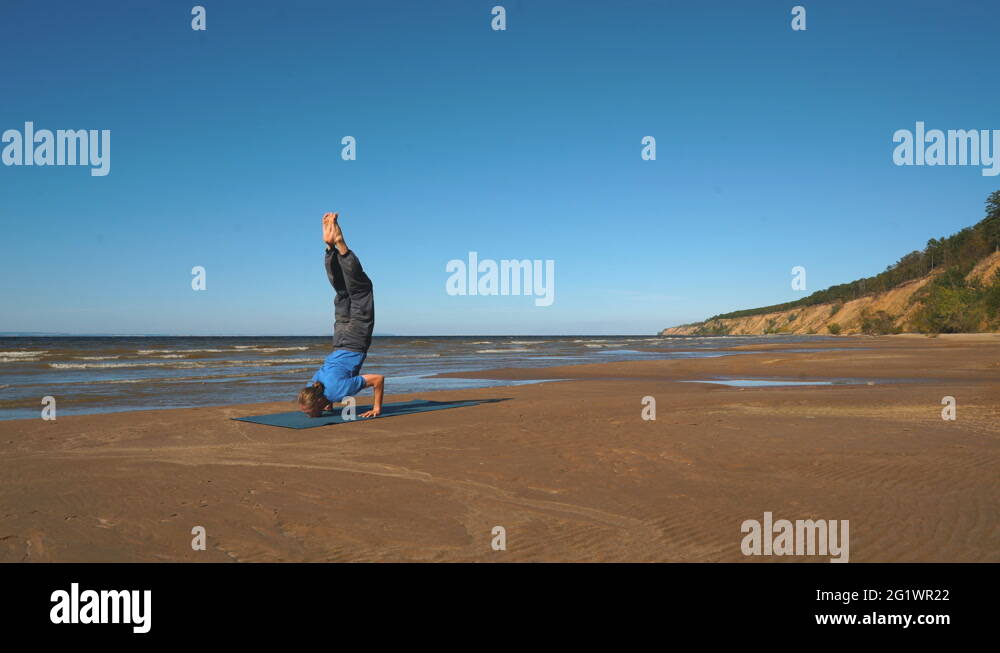 Handstand yoga pose by man on the beach near the ocean Stock Video ...