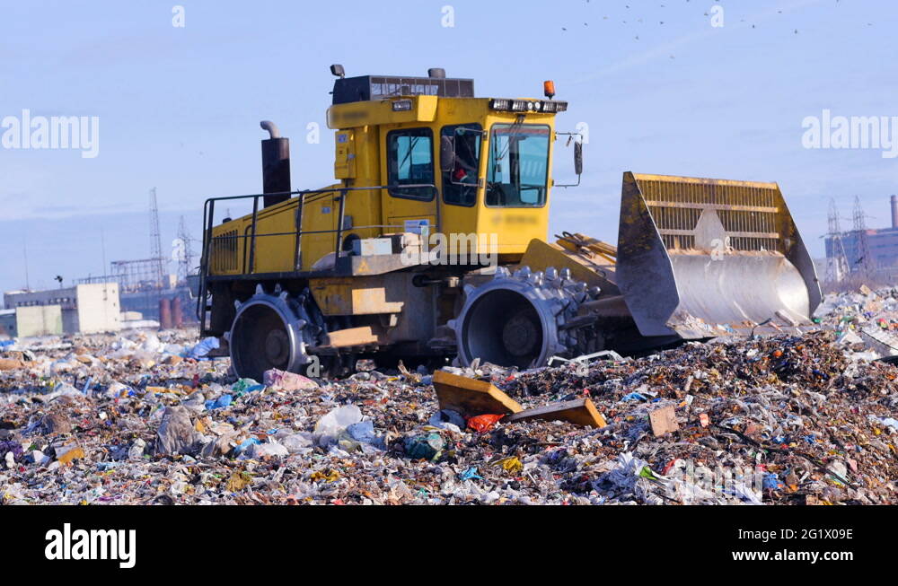 A landfill compactor moves with a raised blade at a city landfill ...