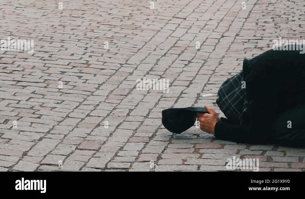 Poor man kneels on the pavement with his outstretched hand and black ...