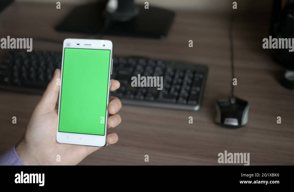 Manager in the workplace using his smartphone with green screen ...