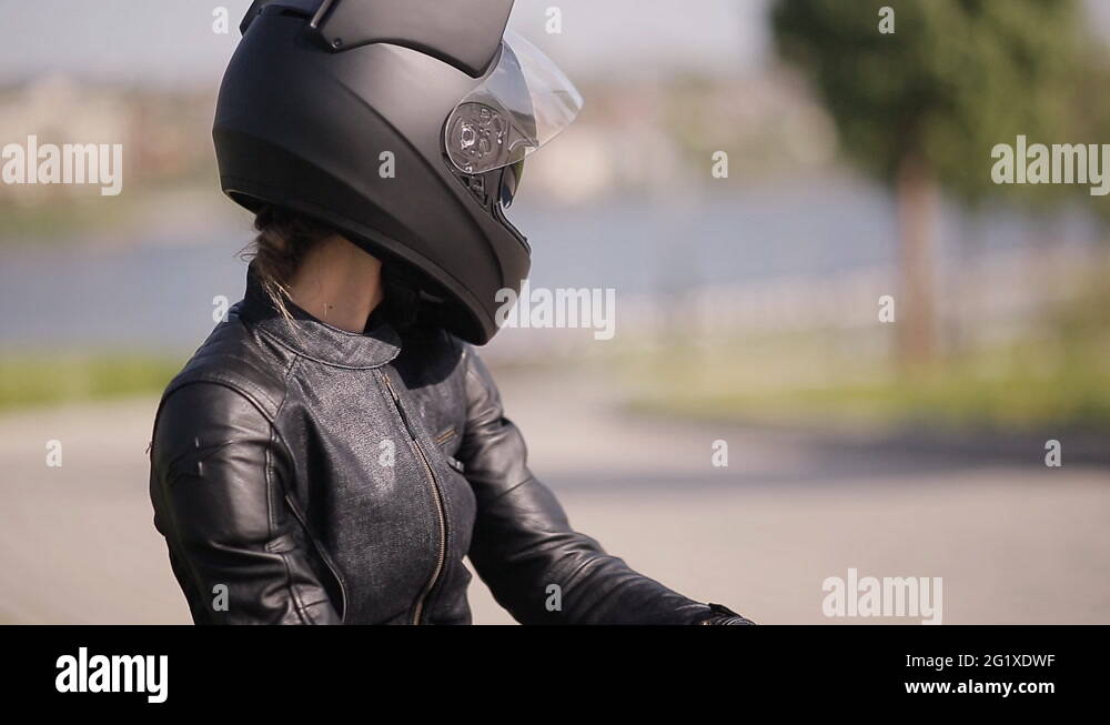 girl in a leather jacket and a motorcycle helmet on her head sits at ...