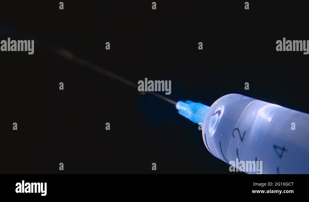 From the needle of the plastic syringe a jet of water, saline solution ...