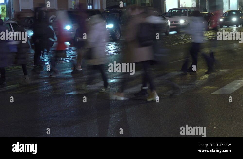 Anonymous people walking at pedestrians crossing crosswalk in the night ...