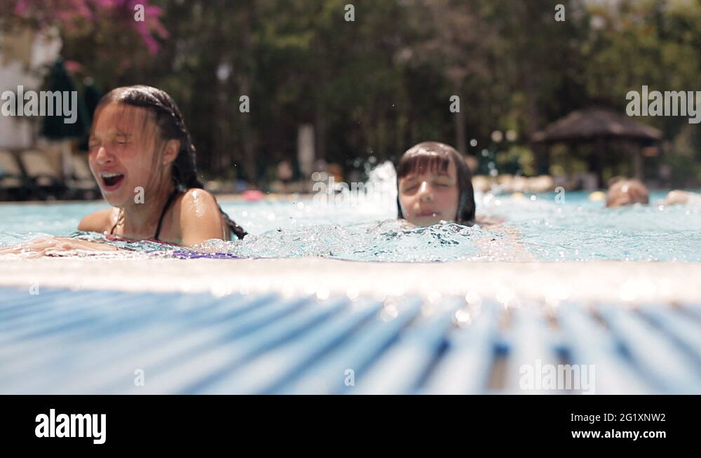 happy girls make a swim and dive in the pool and show the thumbs up ...