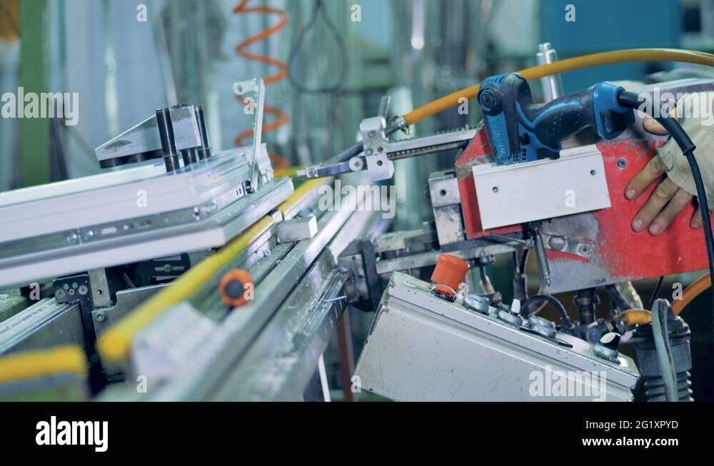 Worker tightening the screws with a screwdriver at a industrial factory ...