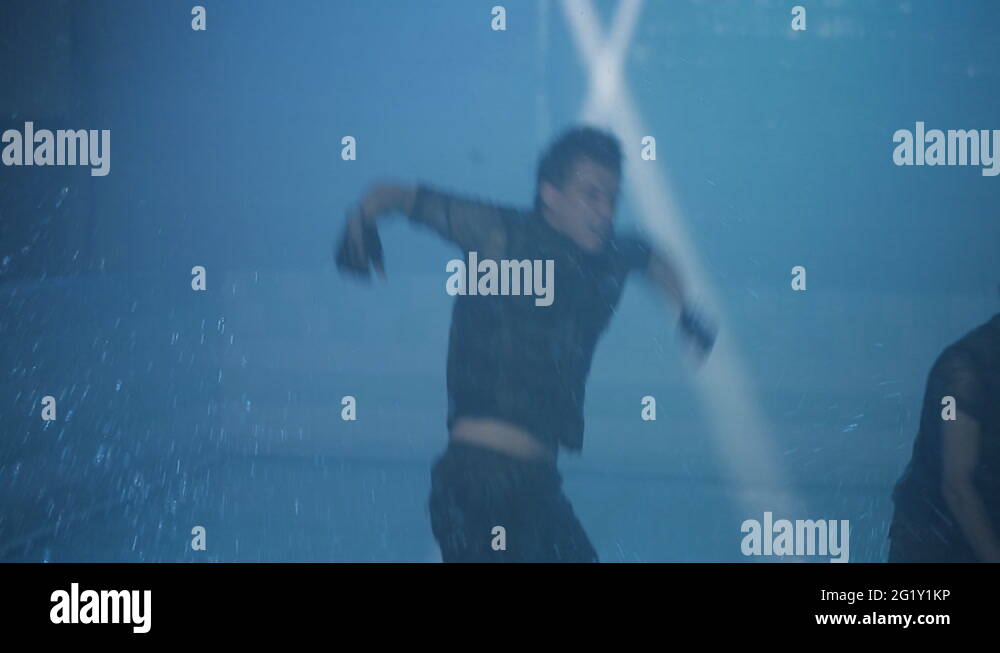 A group of guys are dancing active dance in water with splashes in the ...