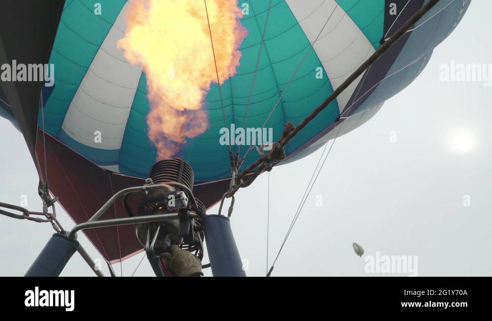 Hot air balloon. Burner directing flame into envelope on background ...