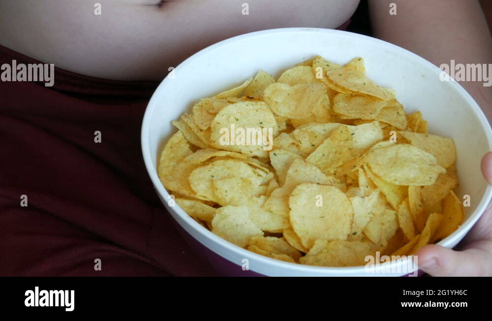 Thick boy boy eating potato chips. Folds of fat on abdomen of the child ...