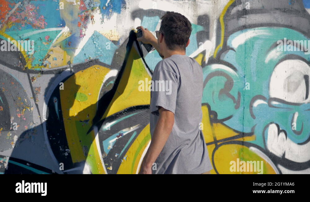 Graffiti artist is painting a black triangle on the yellow letter Stock ...