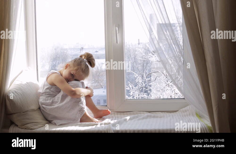 Sad little girl sitting on window sill. Winter outside the window Stock ...