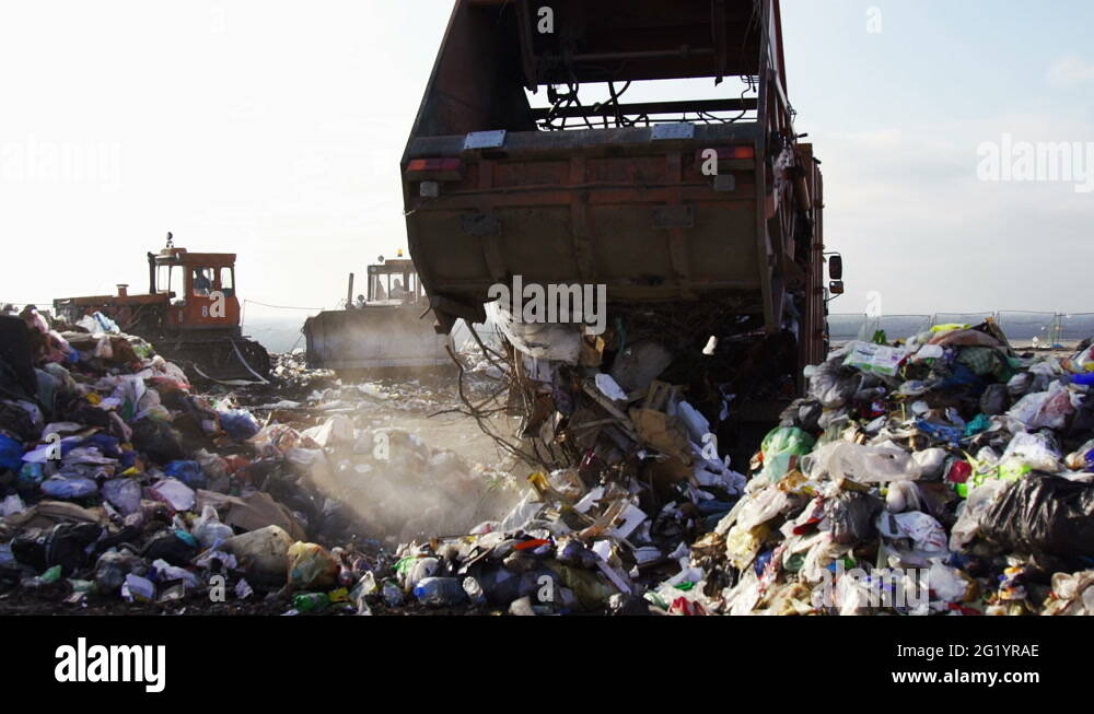 Garbage truck unloads garbage to the dump.Bulldozers work in the ...