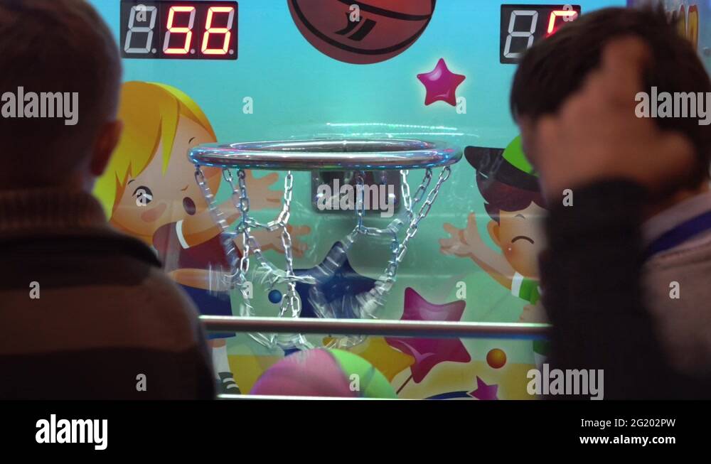 Two boys throwing ball into basketball hoop, playing indoor activity ...