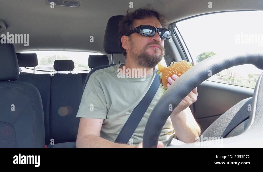 Man starting to drive eating burger being late in traffic Stock Video ...