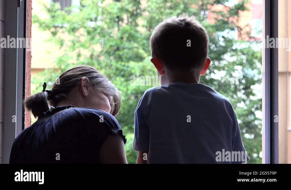 Mother and child look at window, mom caressing playful kid back ...