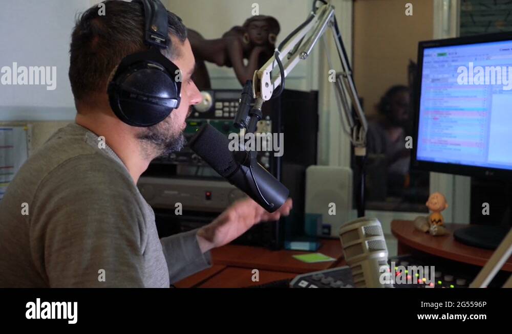 Radio presenter at the microphone in a live radio broadcast studio ...