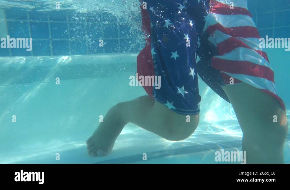 A boy walking down stairs into a pool at a hotel resort, slow motion ...