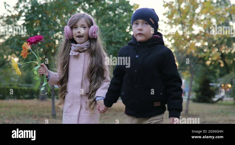 Two children walking in the park. A little boy and a little girl are ...