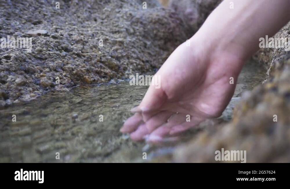 Woman's hand playing with rain water in a puddle in stone. Slow motion ...