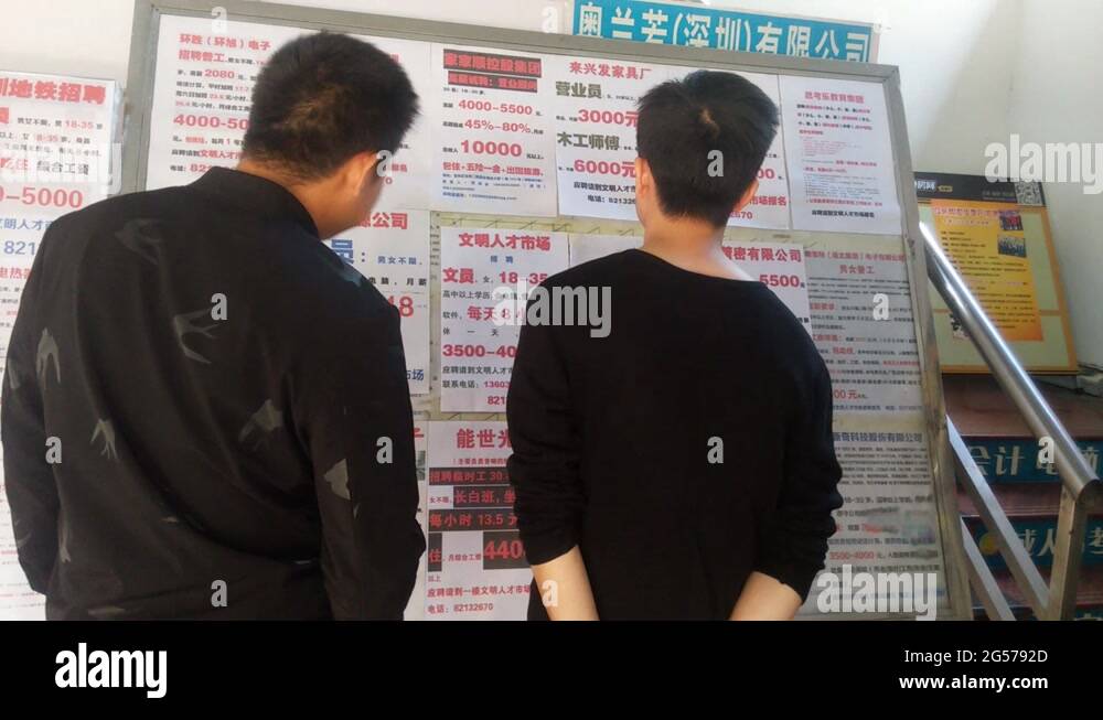 Shenzhen, China: Men Look at a job advertisement at an employment ...