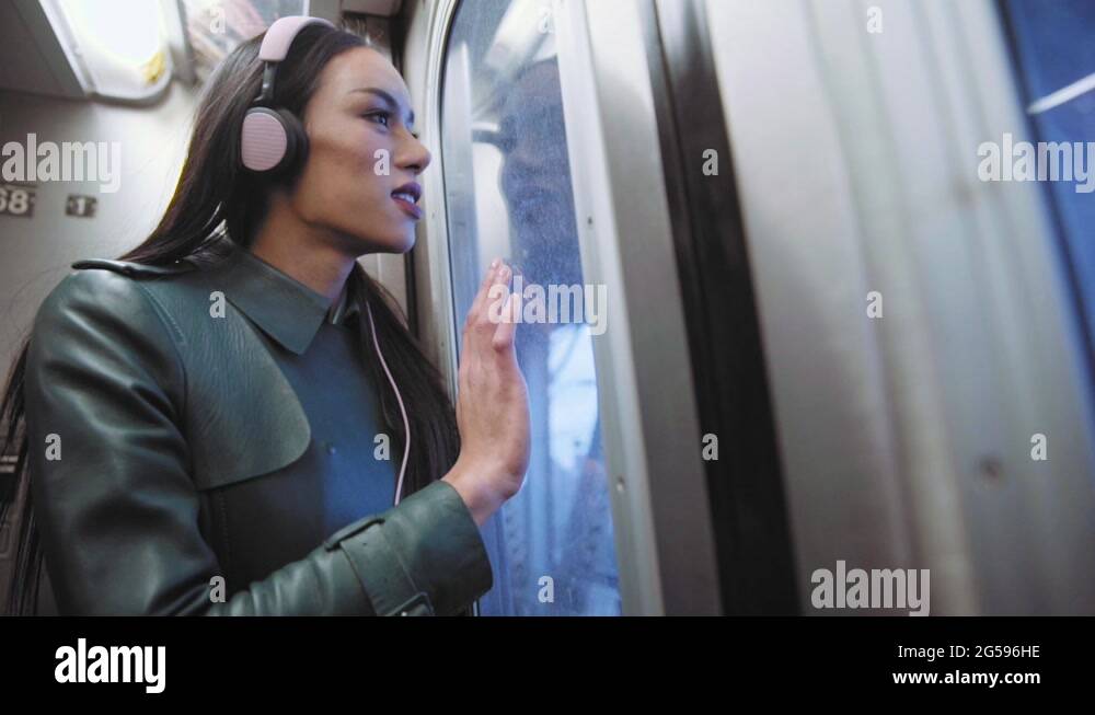 Thai transgender woman listening to headphones on subway train Stock ...