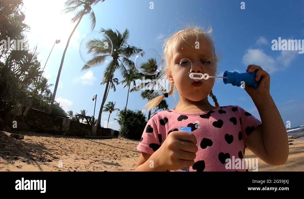 Cute little girl is blowing soap bubbles on the beach gopro rapid Stock ...