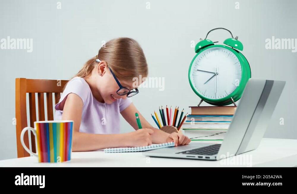 School girl child 7-8 years old doing homework with help of laptop ...