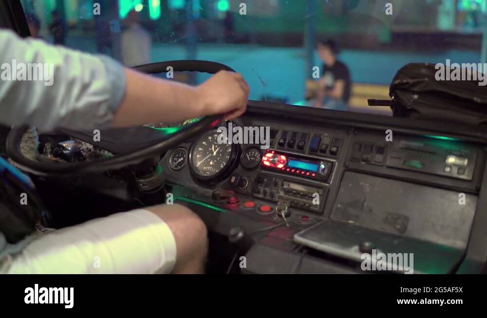 Bus driver sits behind the steering wheel of intercity coach at night ...