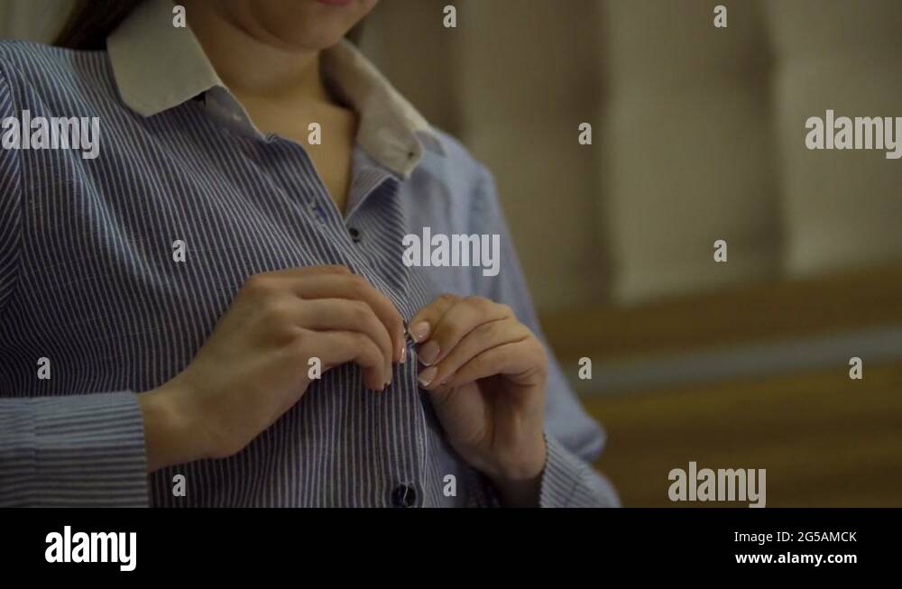 close-up, details. a woman unfastens the top button on her white shirt ...