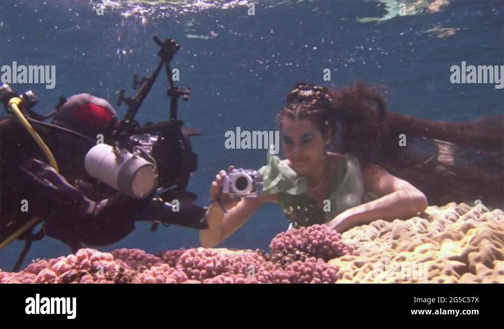 Underwater model free diver poses for camera on background of corals in ...