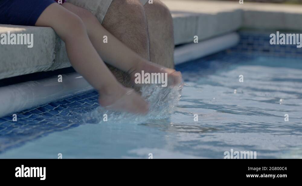 Detail of girl's legs splashing feet in swimming pool next to dad 4K ...