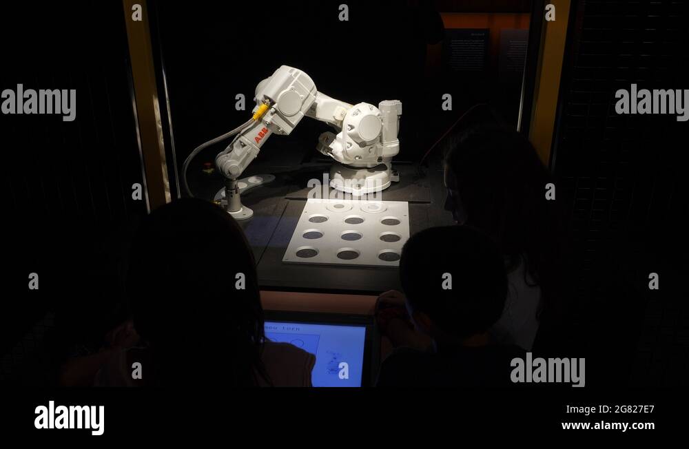 Children play tic-tac-toe game with computer, robotic arm move discs to ...