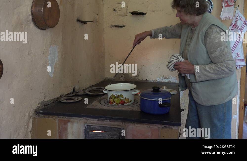 Grandmother woman cooking in pots on old furnace stove fire. 4K Stock ...